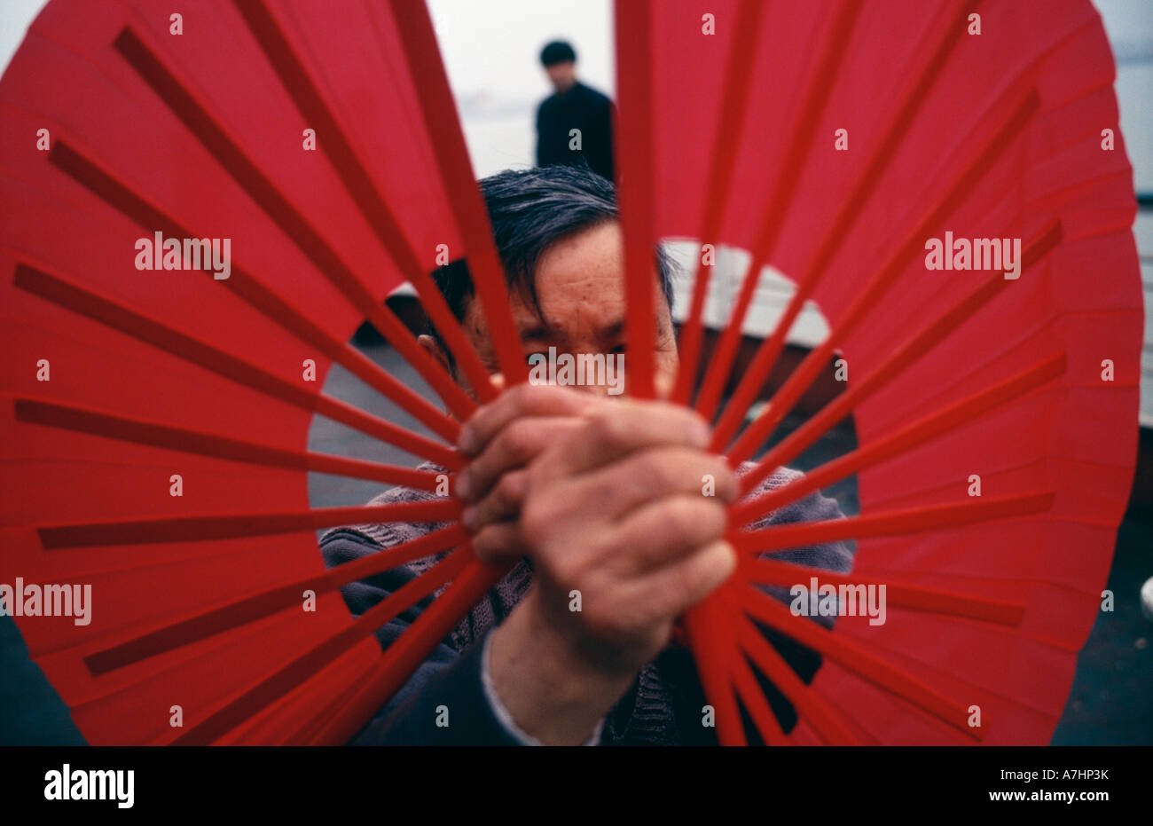 A Chinese man holds up two red fans Stock Photo - Alamy