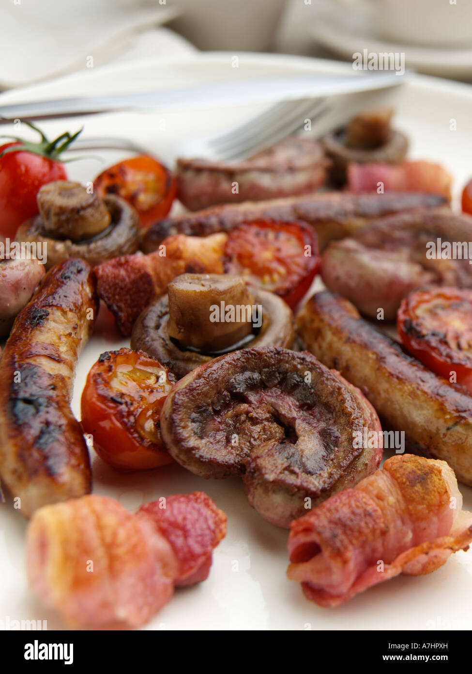 A plate of mixed grill chipolata sausages kidneys mushrooms and grilled ...