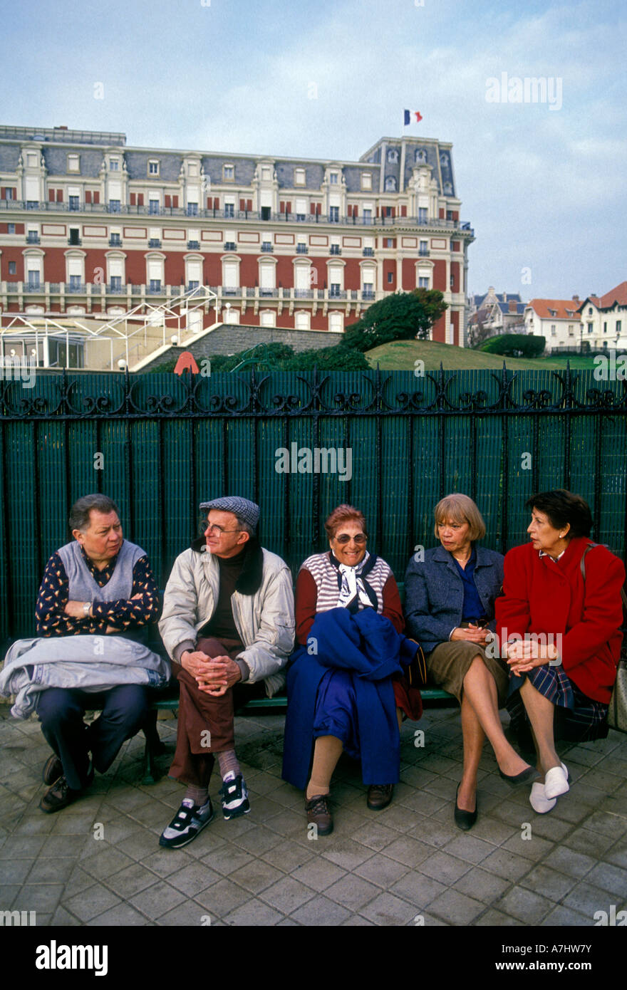 French women and men friends sitting on bench and talking in the French ...