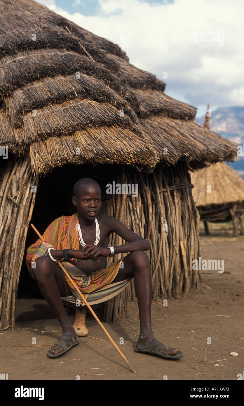 Karimojong boy at his hut in a village at the base of Mount Kadam 3068m ...