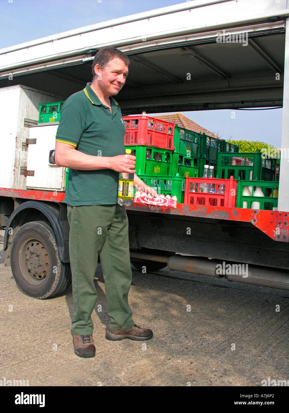 milkman on round with a motorised driven float delivering sundry ...