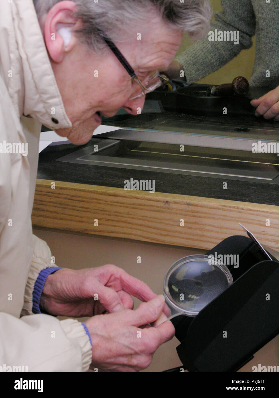 elderly woman using magnifying glass making it easier to see the post ...