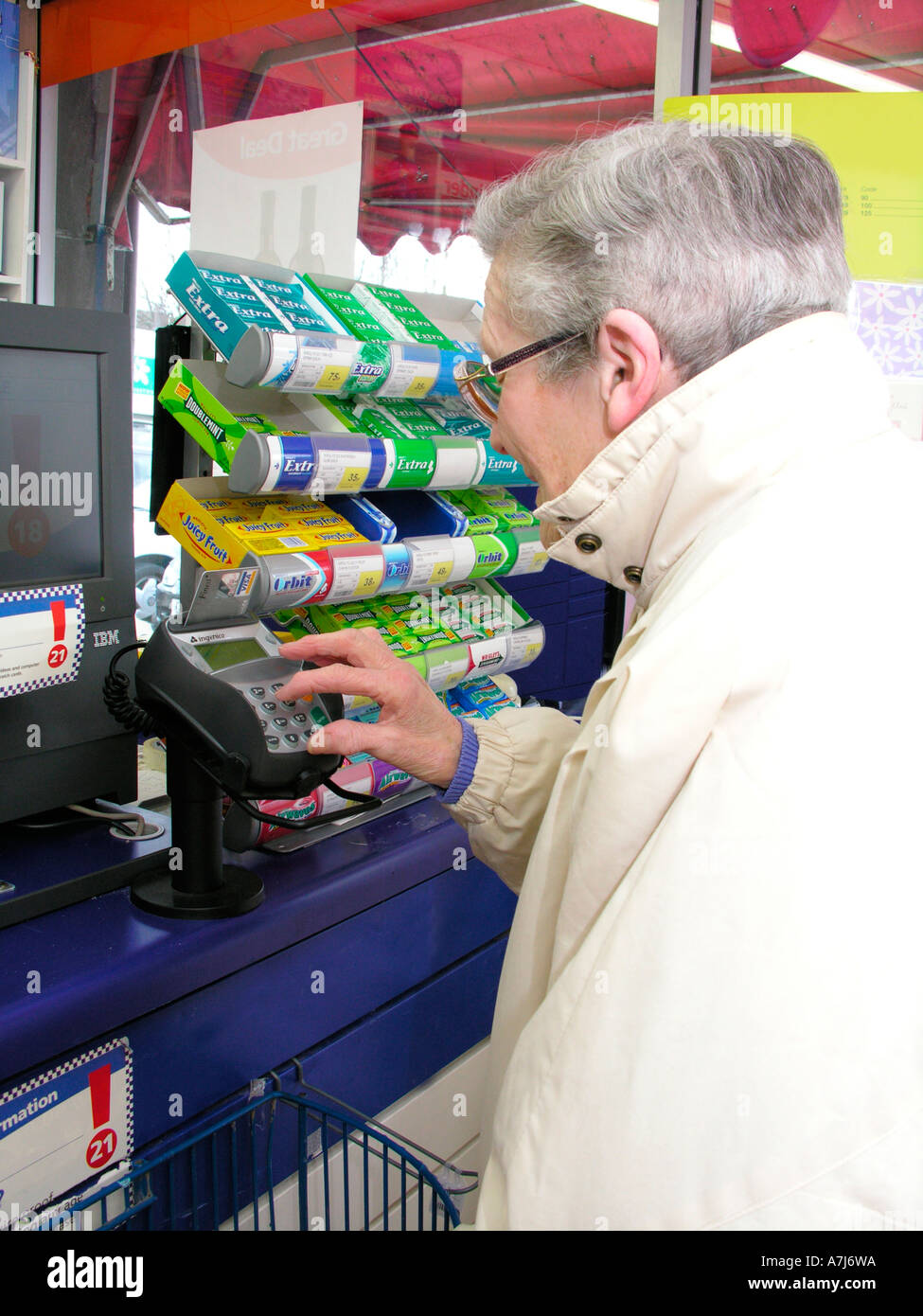 elderly woman using the chip and pin machine at the checkout of a ...
