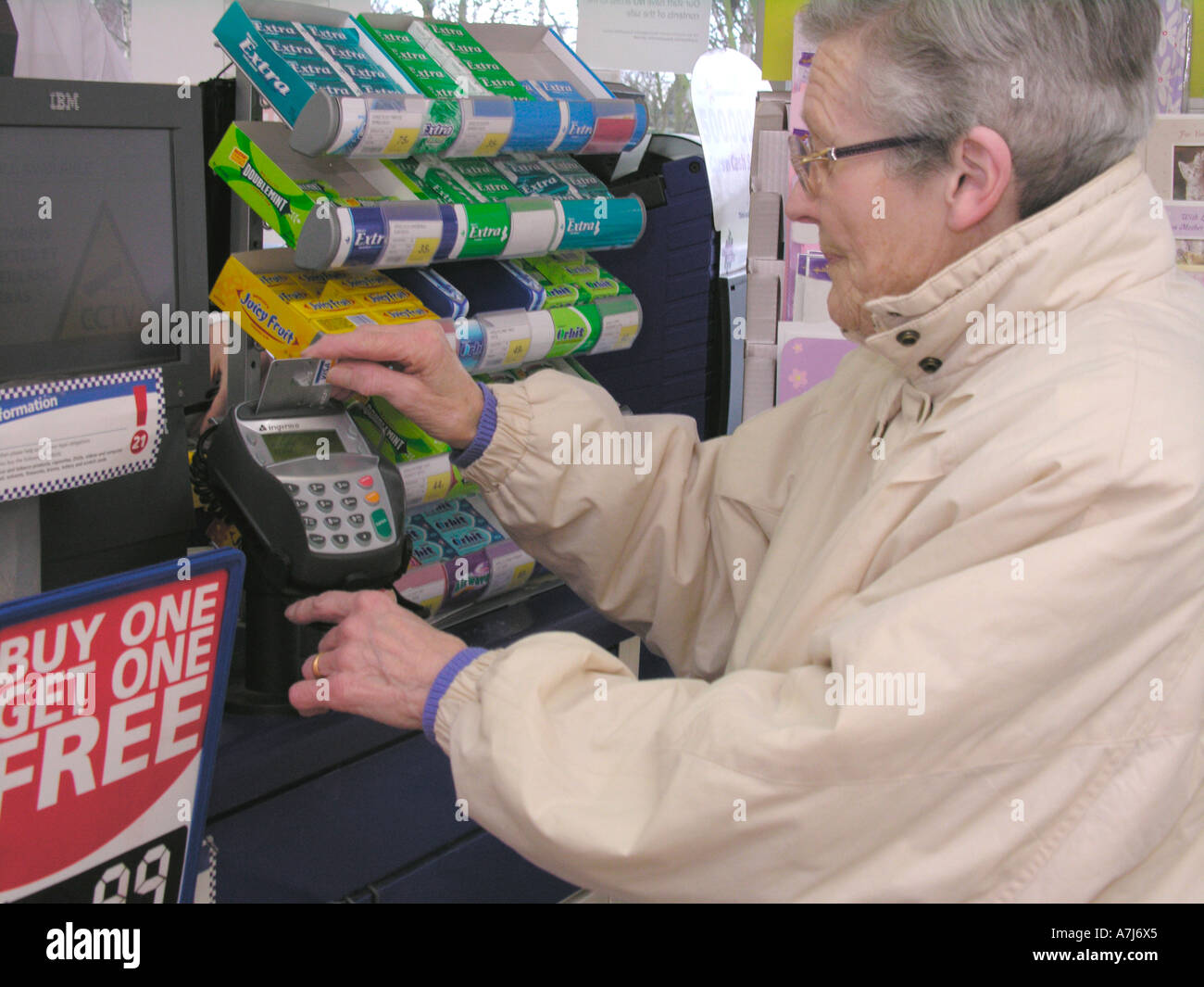 elderly woman using the chip and pin machine at the checkout of a ...