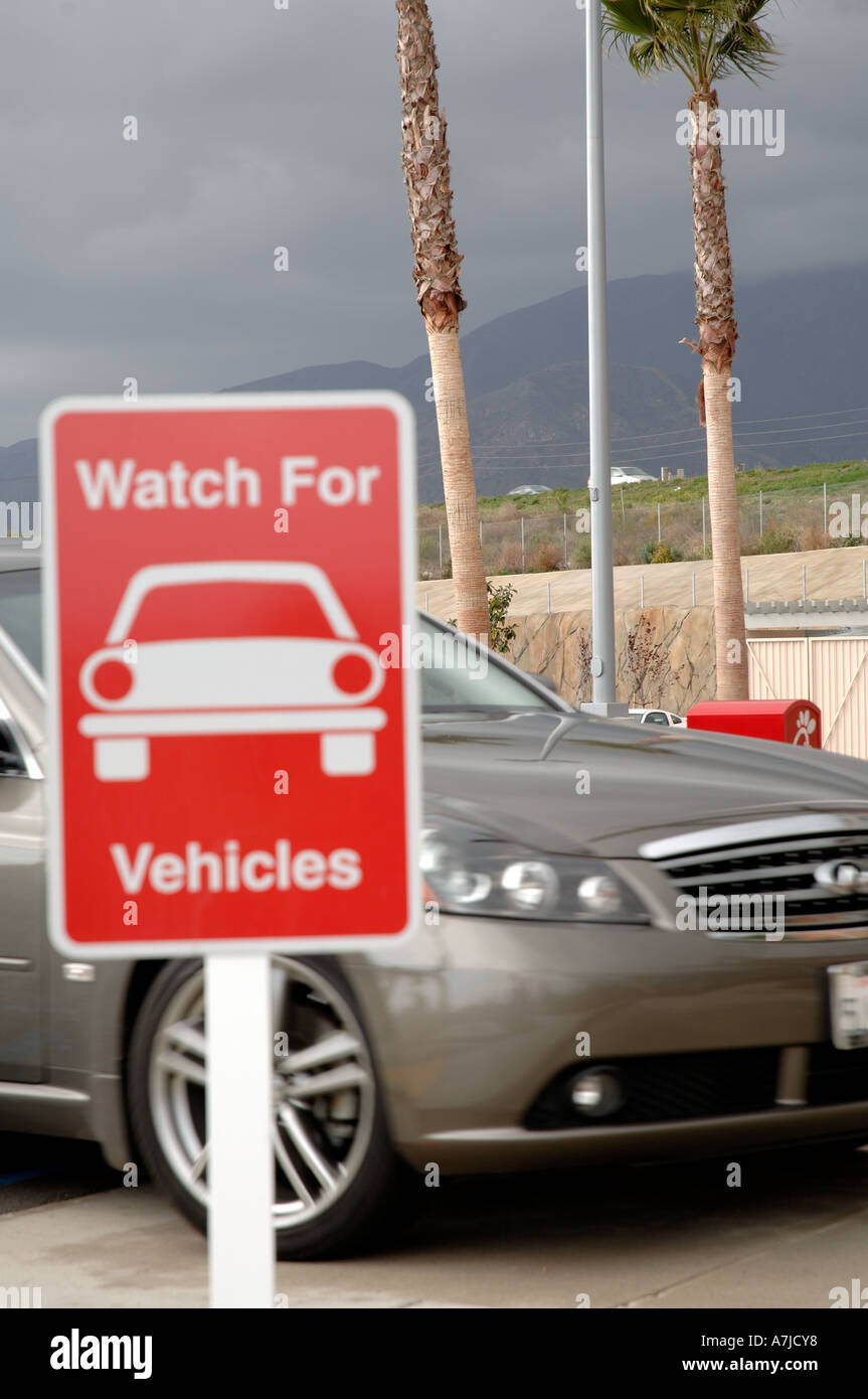 Warning sign reading 'Watch for Vehicles' with car driving by on the ...