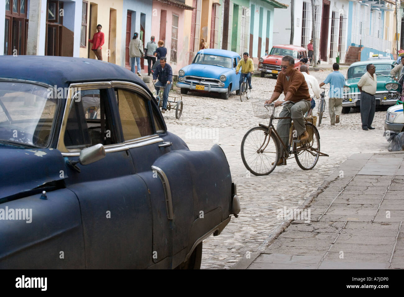 Vintage cars and cyclists dominate this typical street scene in ...