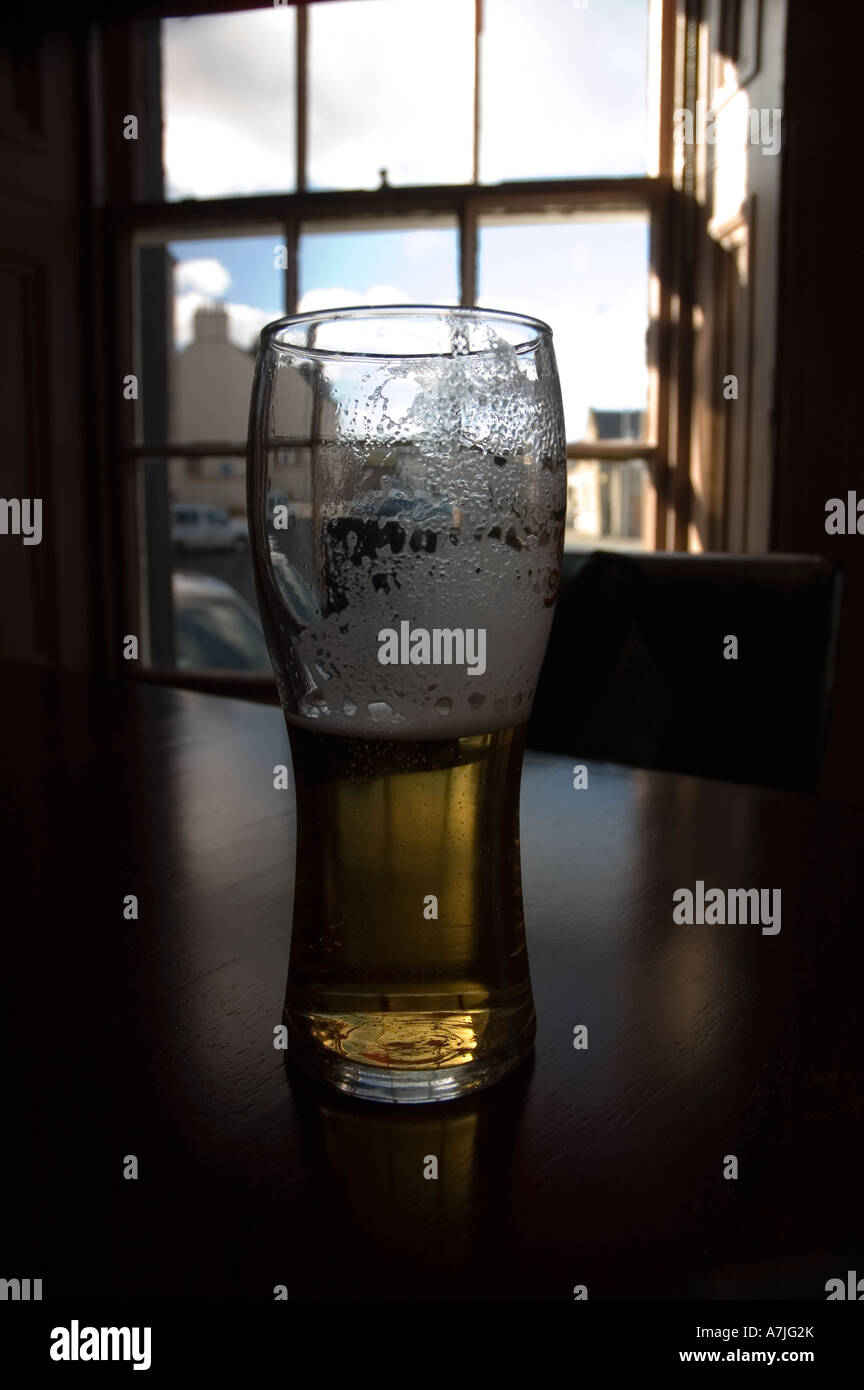 A half full pint of lager Stock Photo - Alamy
