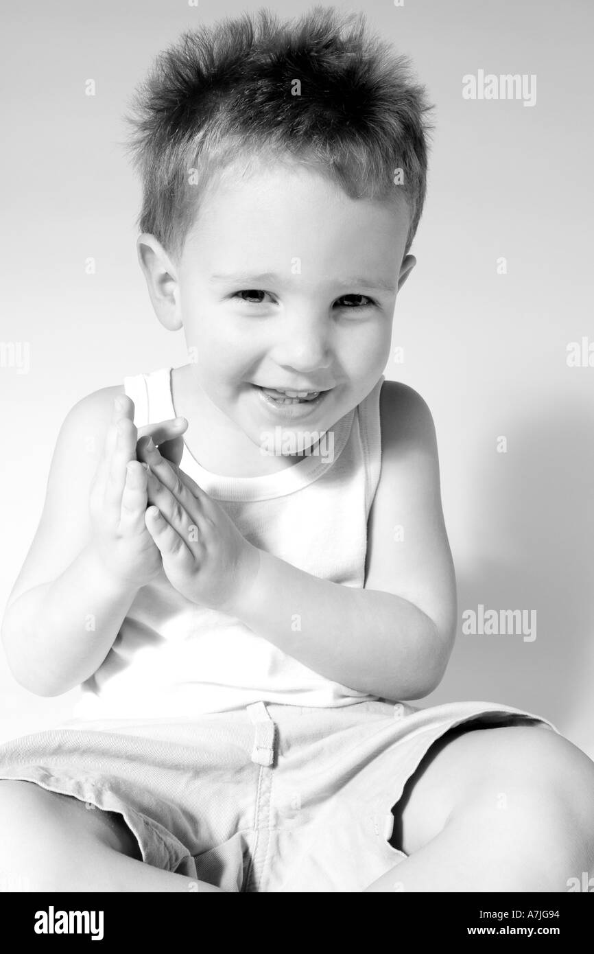 Little boy clasping hands looking into camera Stock Photo - Alamy