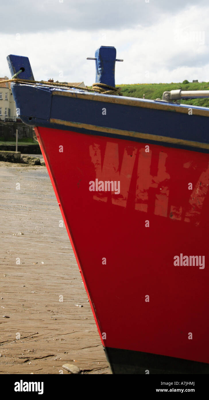 The red hull of a fishing boat moored on Staithes beach Stock Photo - Alamy