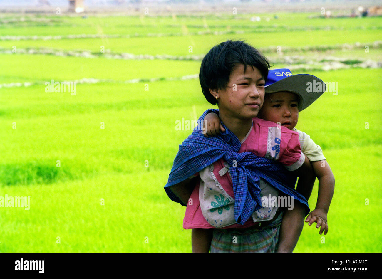 Girl carrying baby brother in rural Myanmar Stock Photo - Alamy