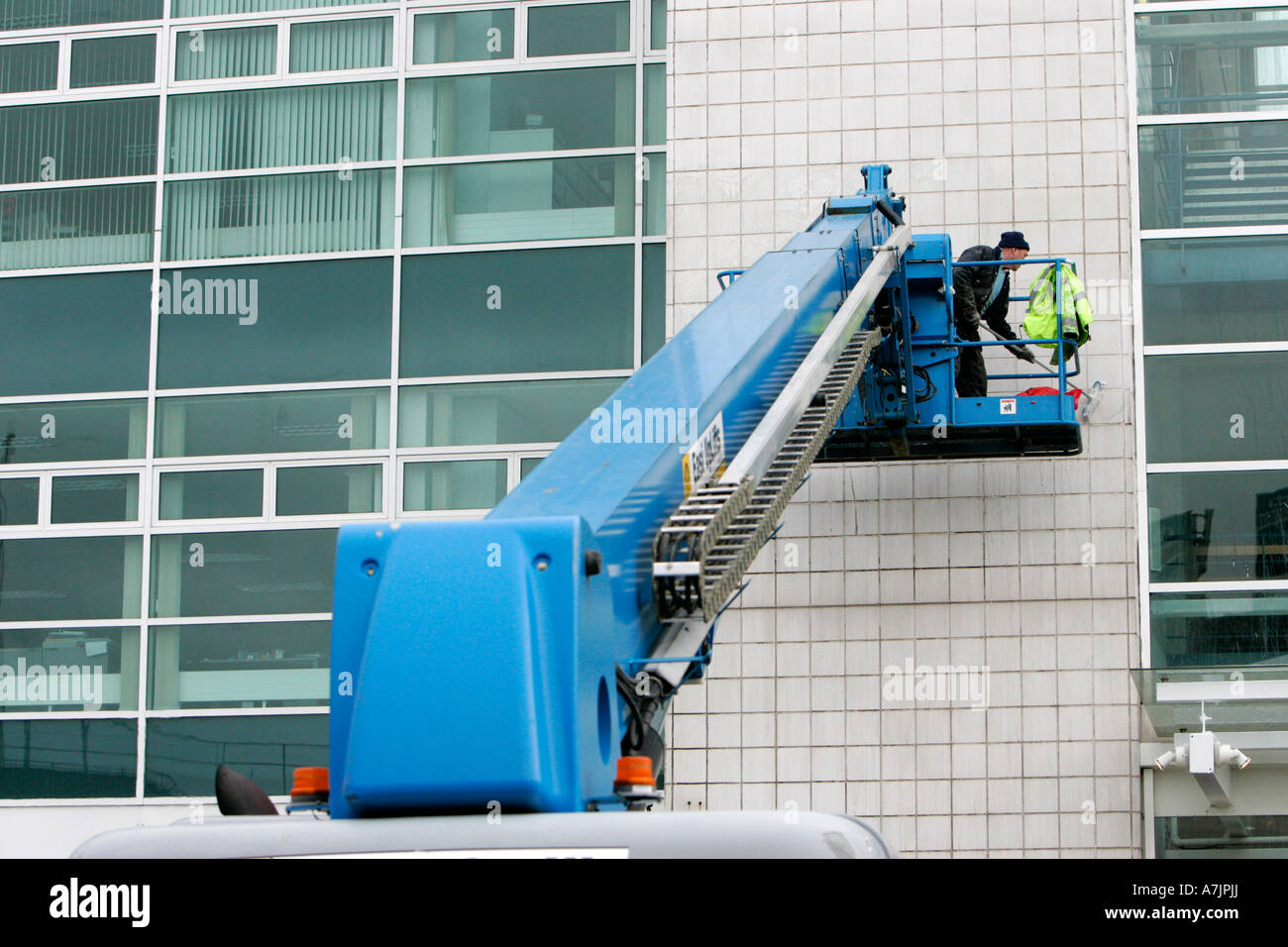 rear view of elevator and worker on elevator platform lift brushing ...