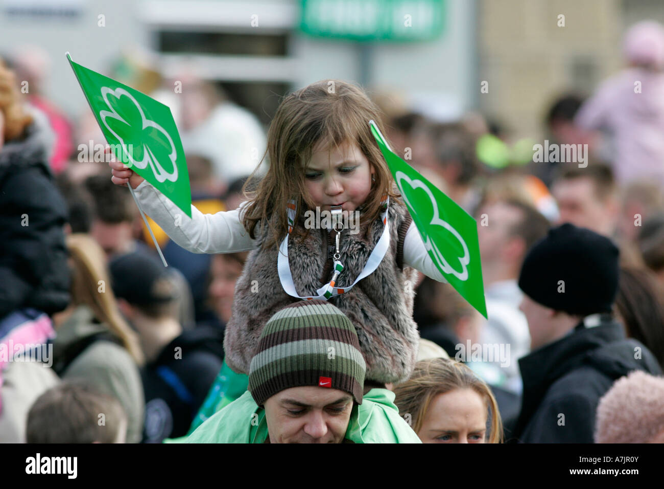 young girl blowing whistle and waving green shamrock flags sitting on ...