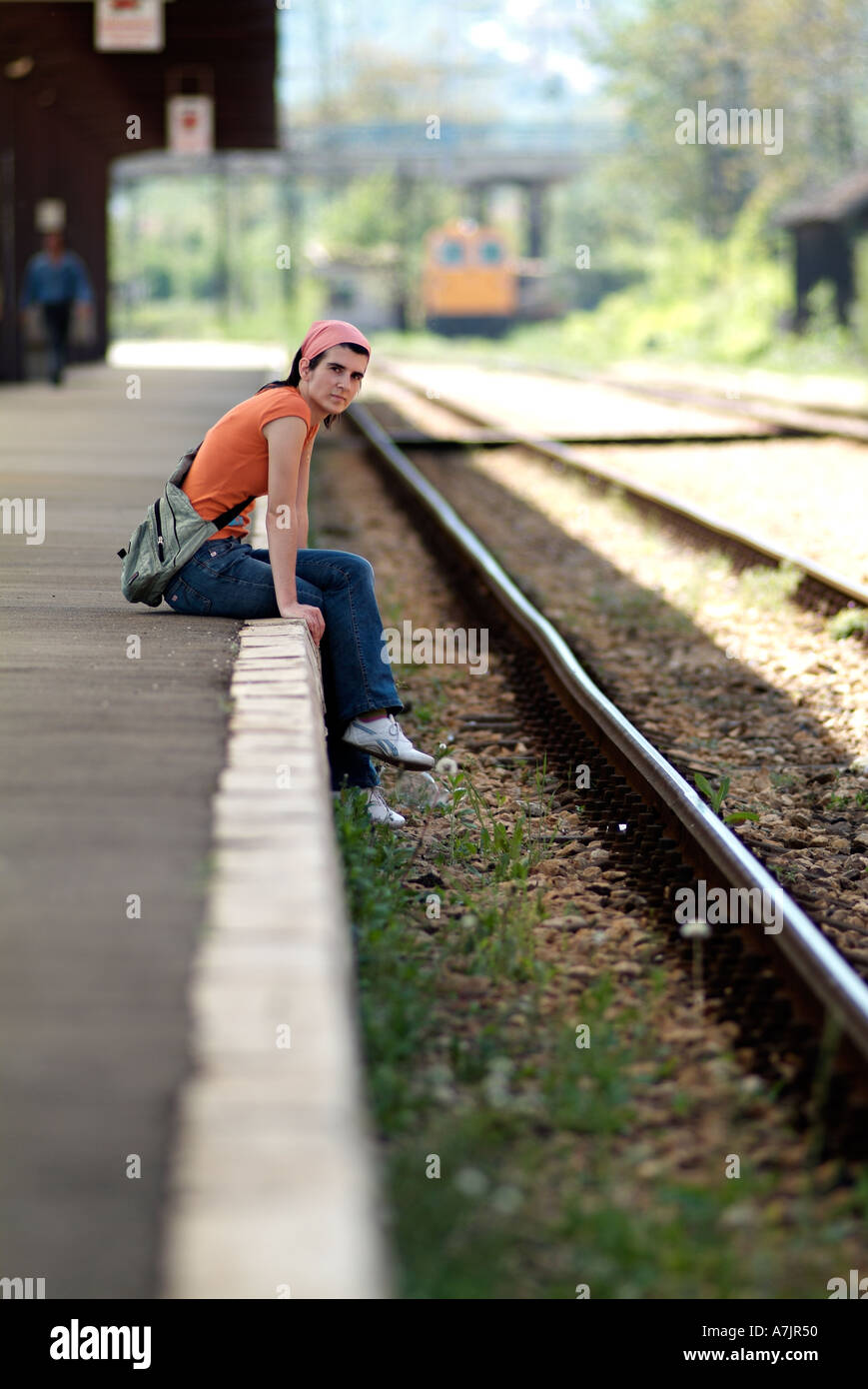 Woman Sitting on a Train Platform Looking Down the Line of the Rail ...