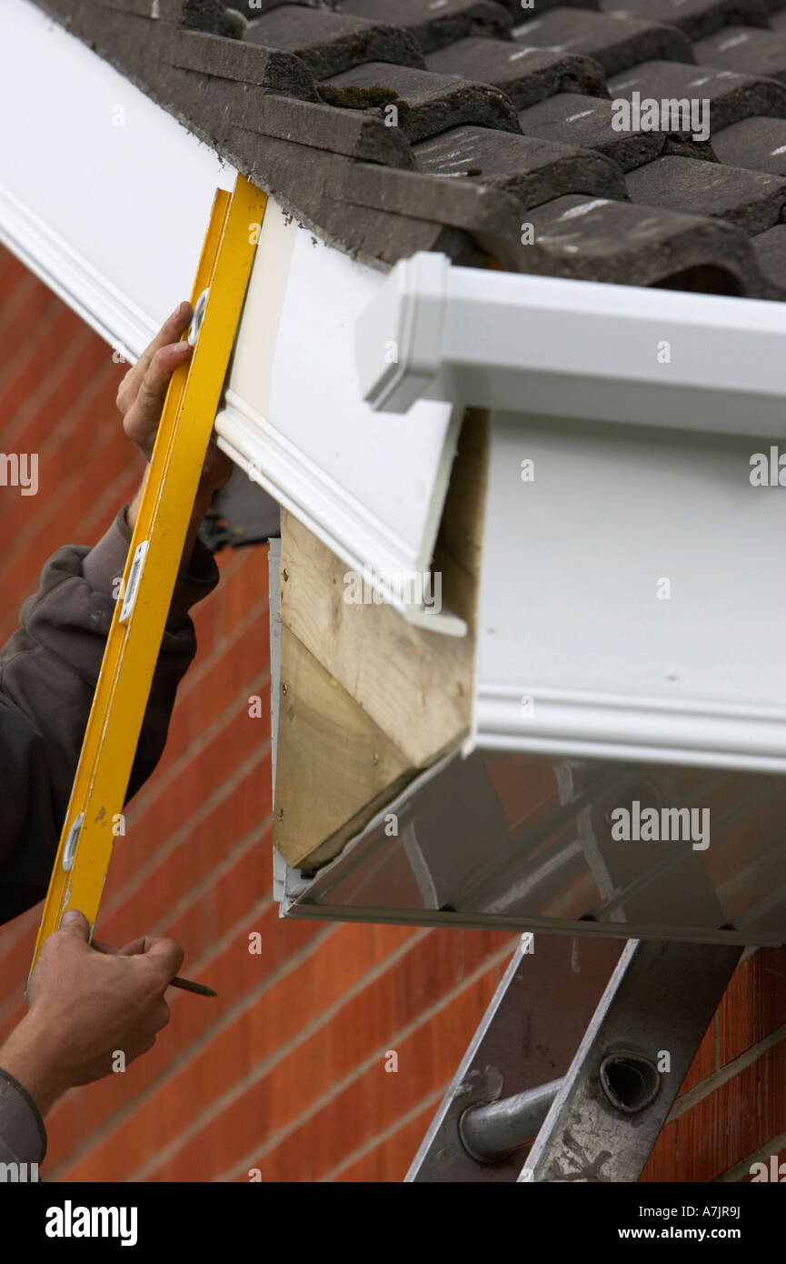 workman measuring and levelling installing white pvc cladding over old ...