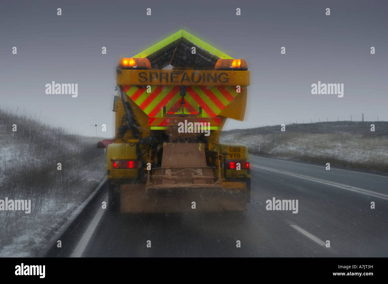 YELLOW GRITTING TRUCK WITH SNOW PLOW SPREADING GRIT SAND AND SALT ONTO ...