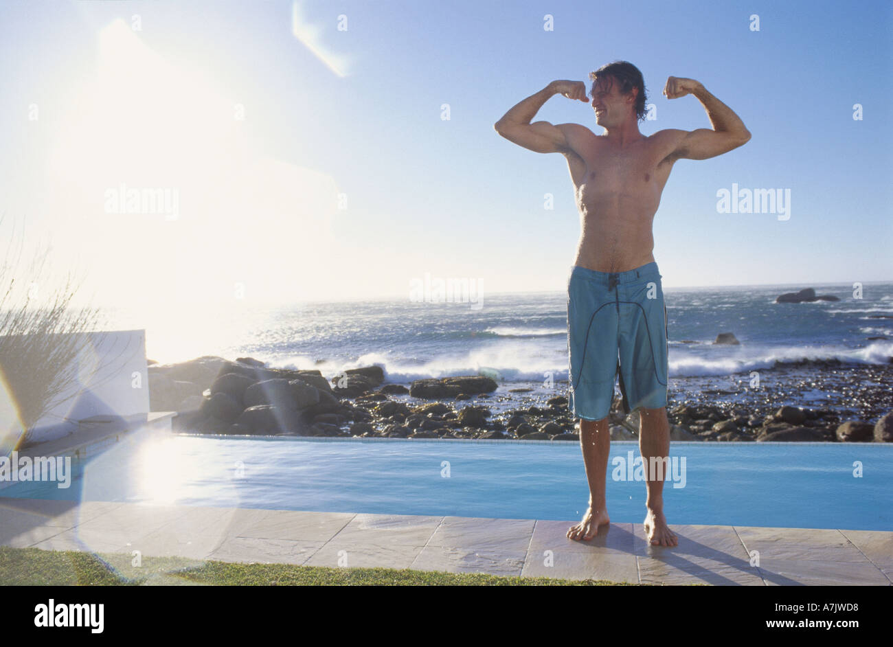Young man flexing his muscles by the pool Stock Photo - Alamy