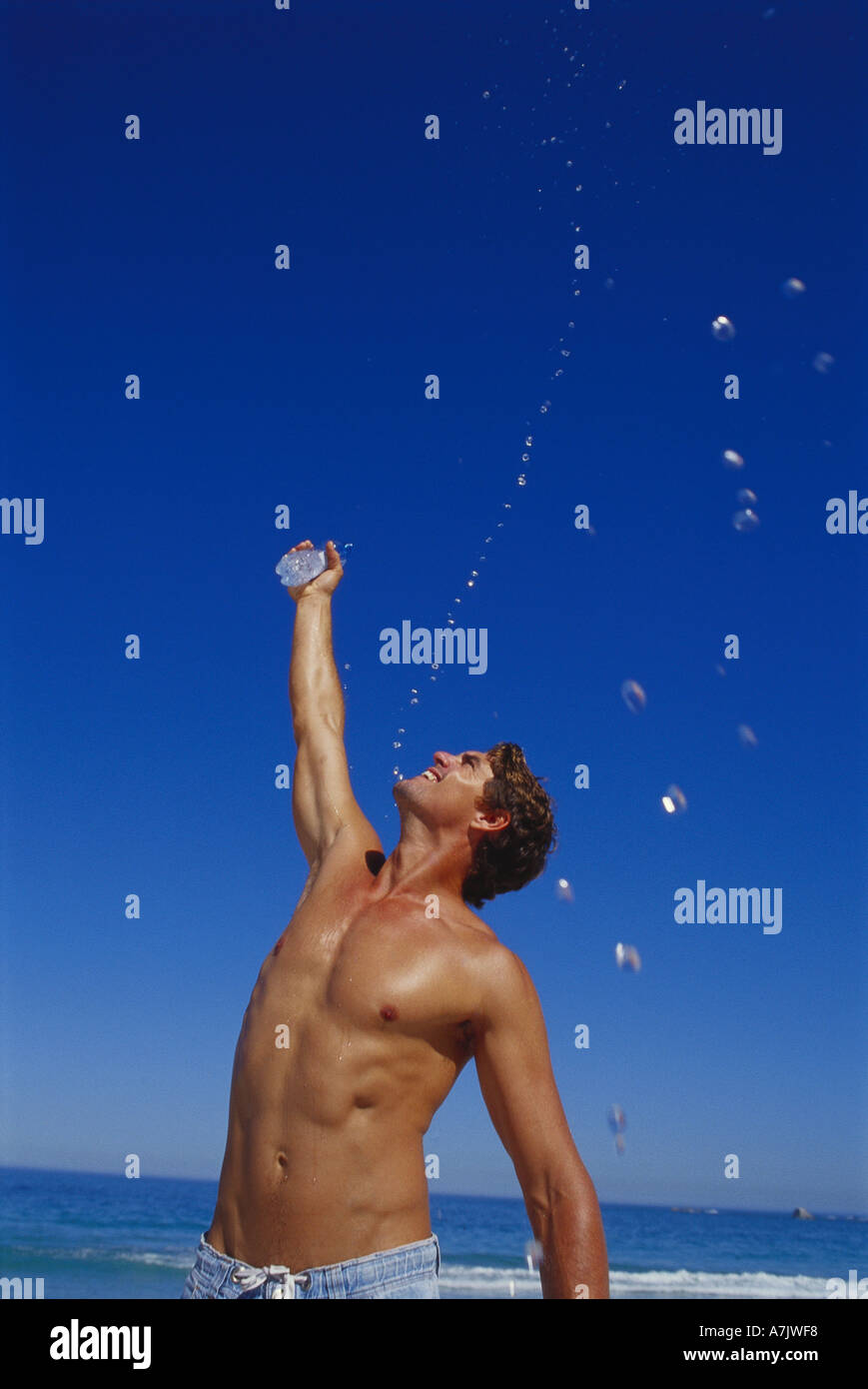 Young man throwing water on the beach Stock Photo - Alamy