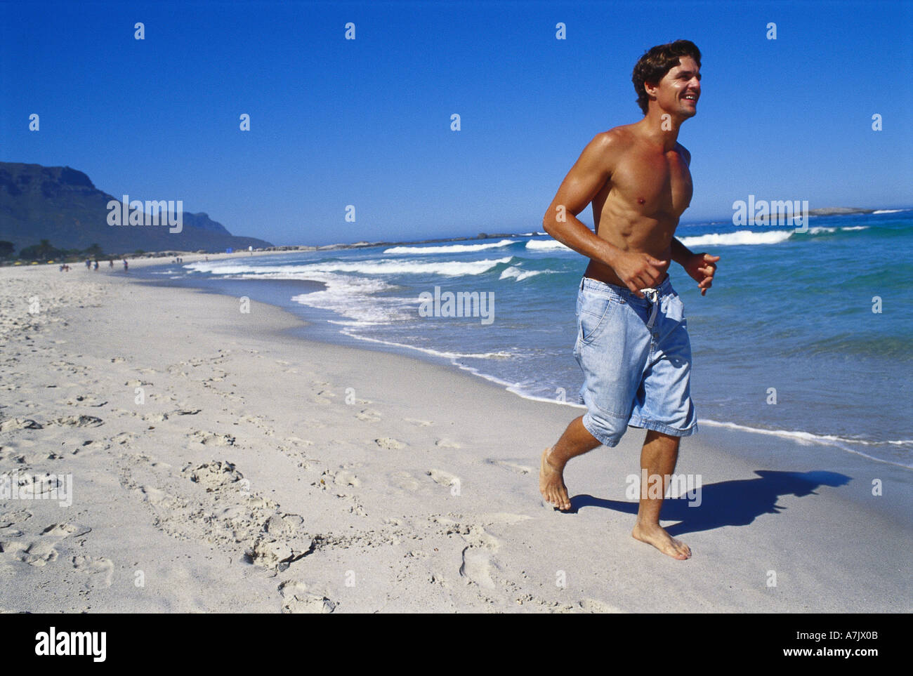 Young man running on the beach Stock Photo - Alamy