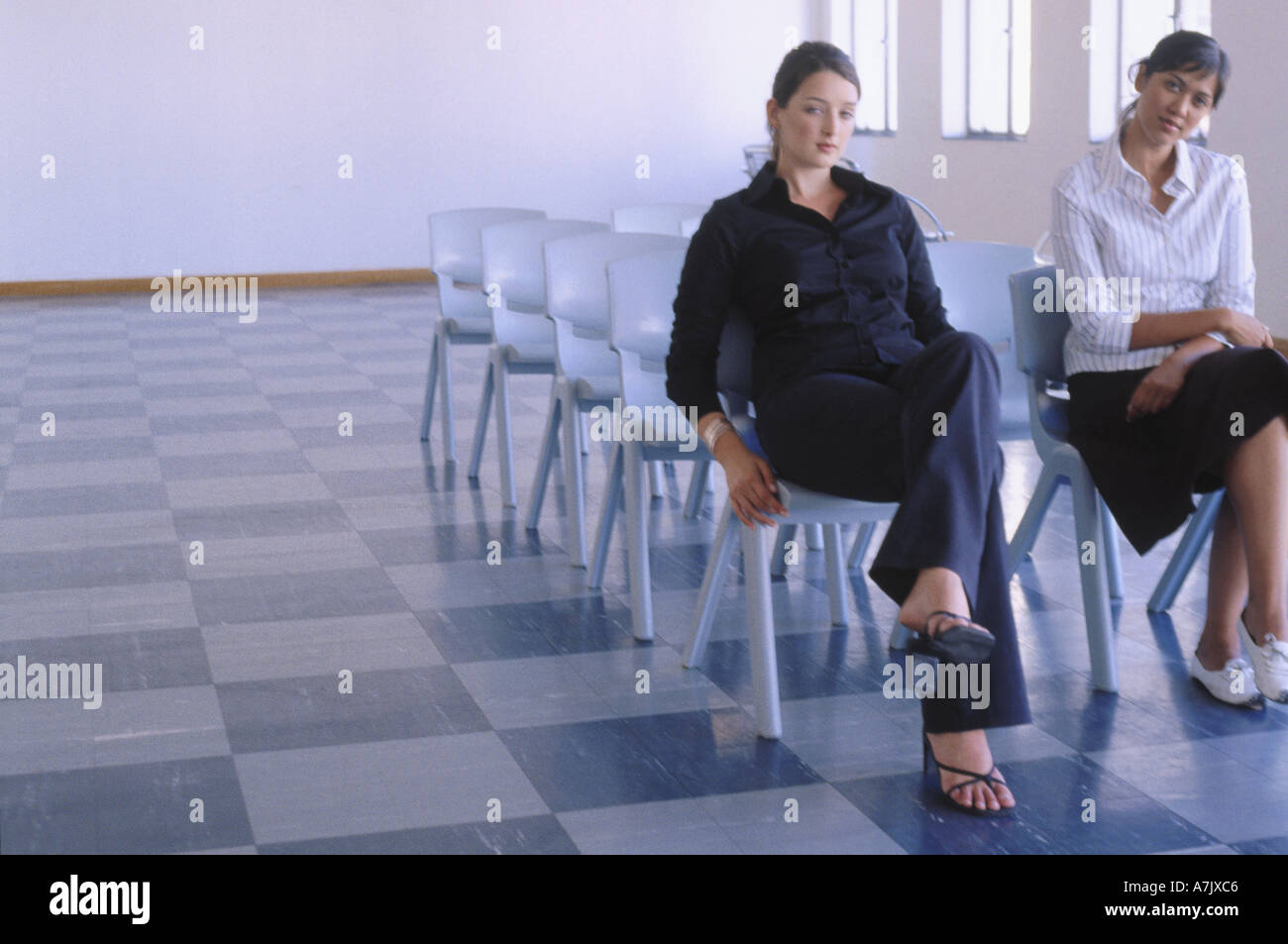 Two young women sitting on chairs Stock Photo - Alamy