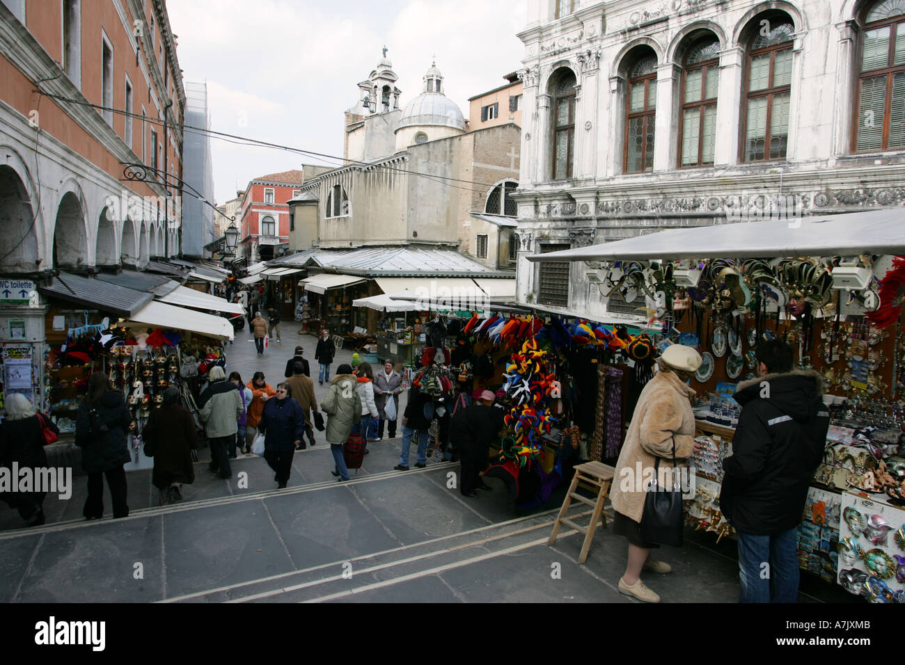 Tourists climb the stone steps of the famous Rialto Bridge passing by ...