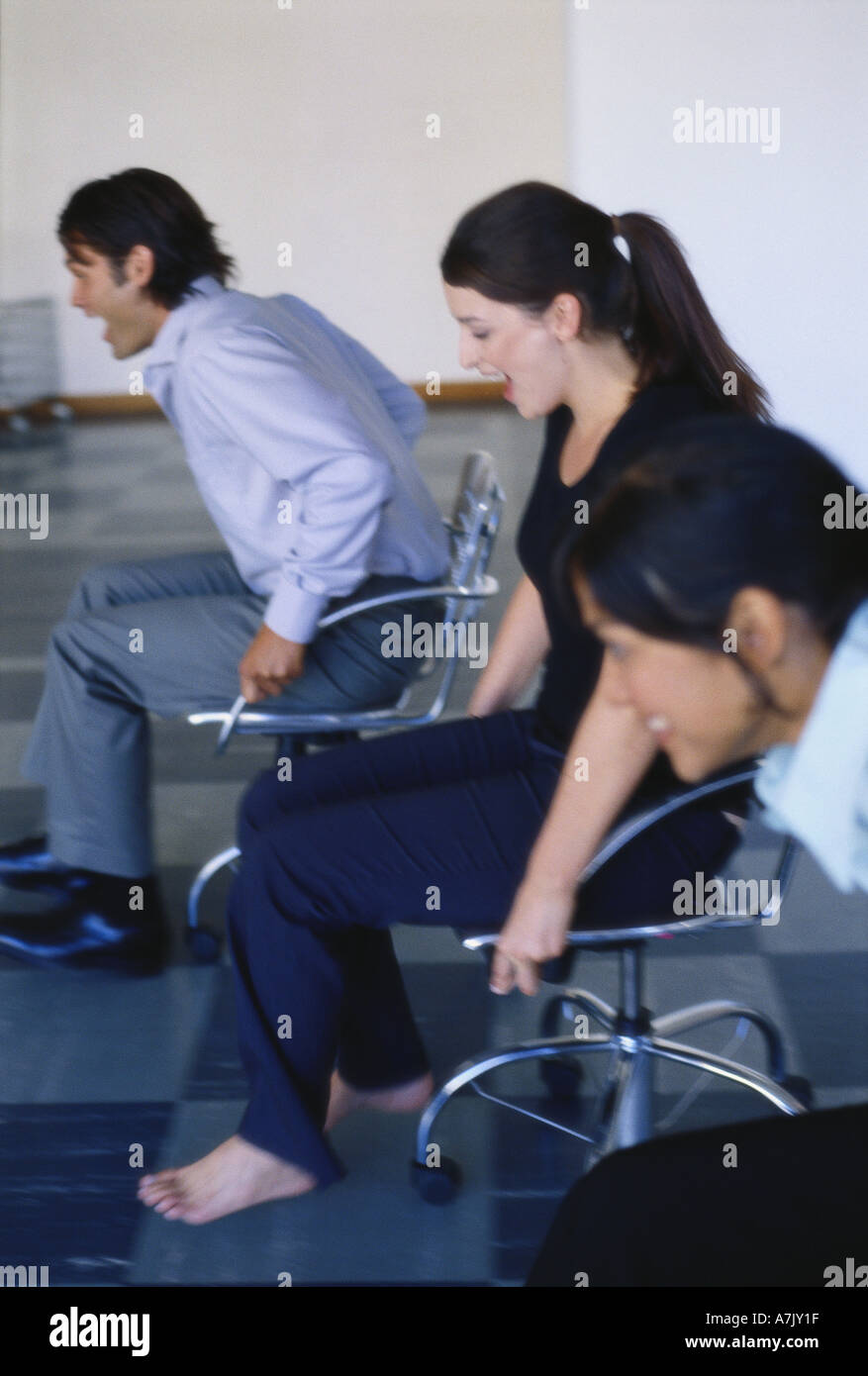 Side profile of two young women and a young man sitting on chairs Stock ...