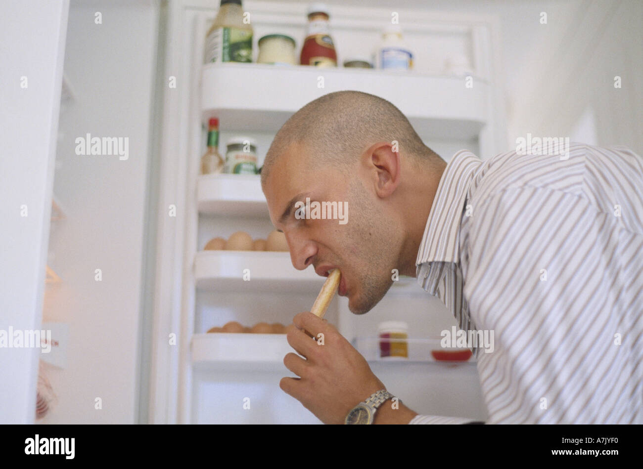 Side profile of a young man eating from a refrigerator Stock Photo - Alamy