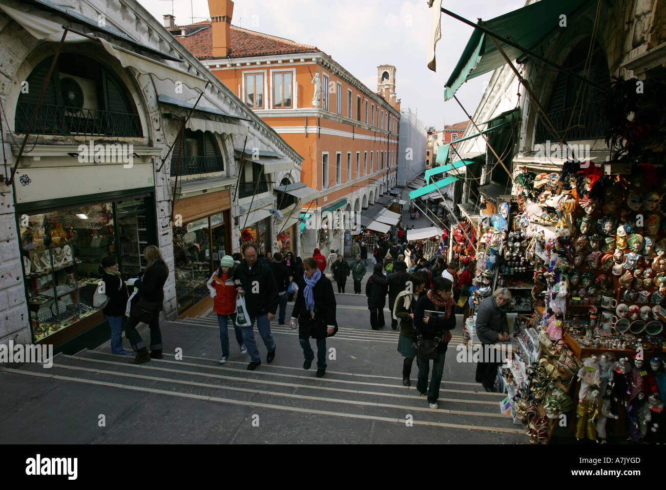 Tourists climb the steps of the Rialto Bridge past souvenir shops, central Venice Italy European ...