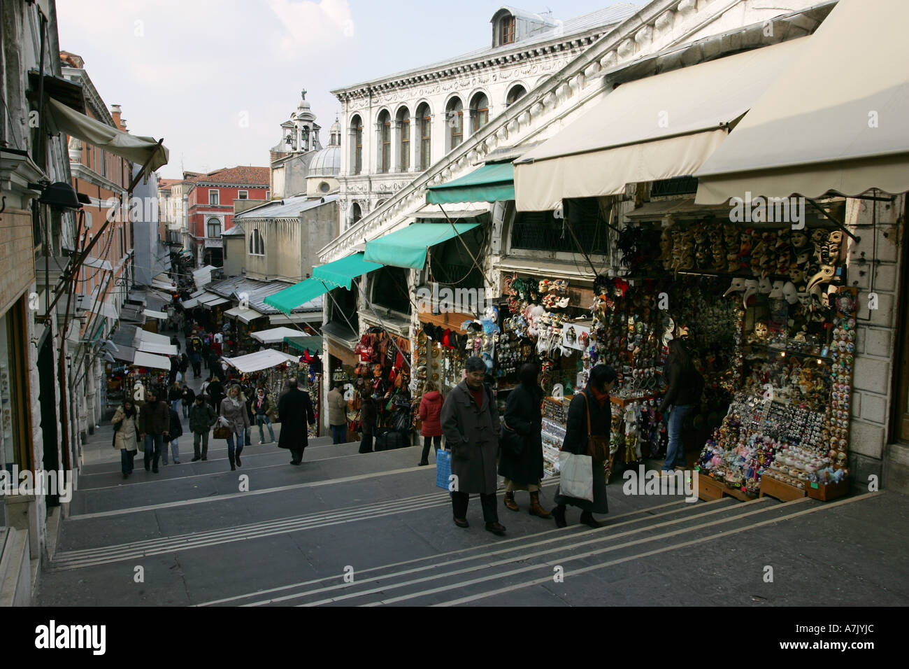 Tourists climb the steps of the Rialto Bridge past souvenir shops, central Venice Italy European ...