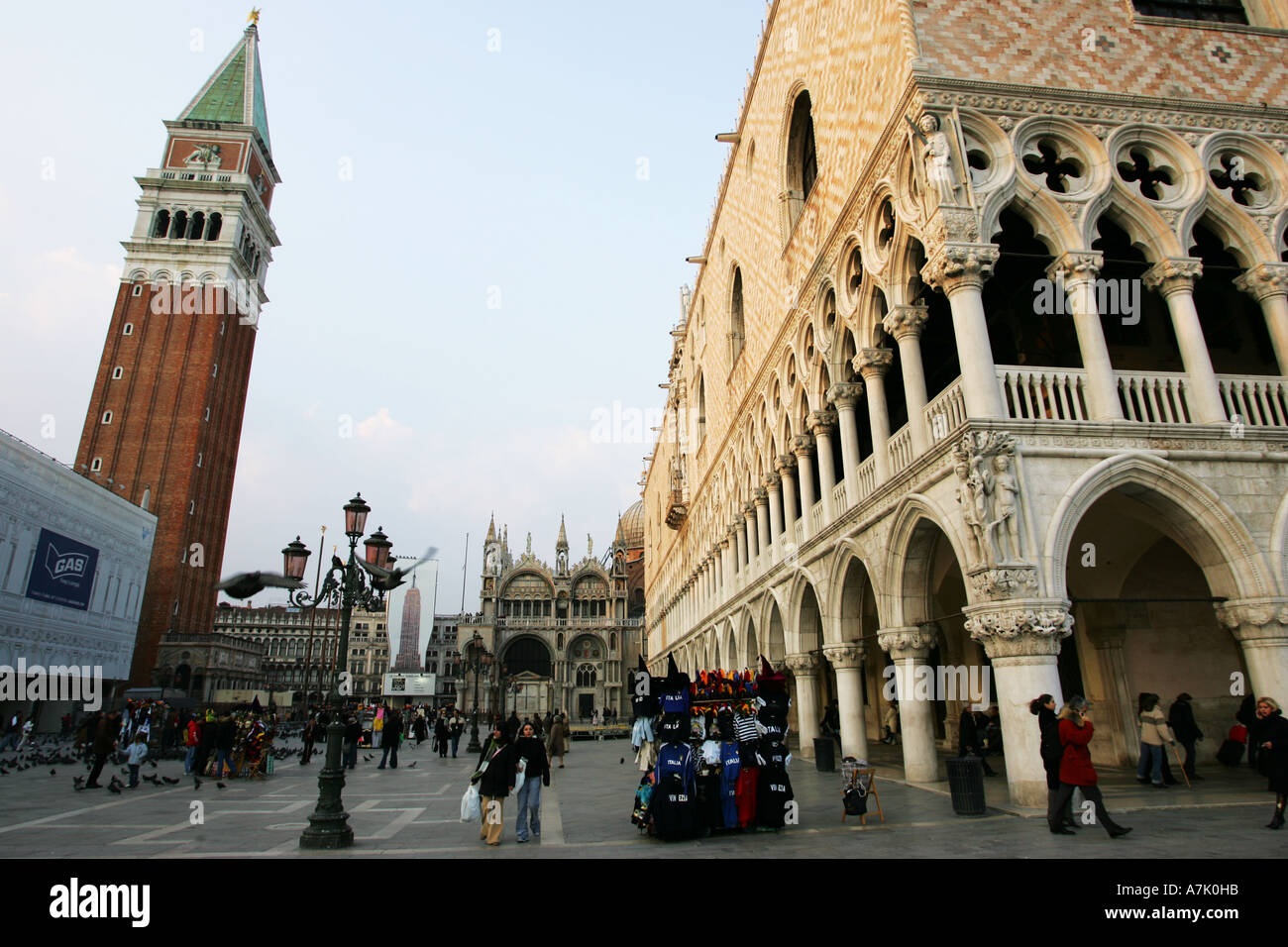 Tourists feed pigeons in early evening sunlight St Marks Square, central venice Italy European ...