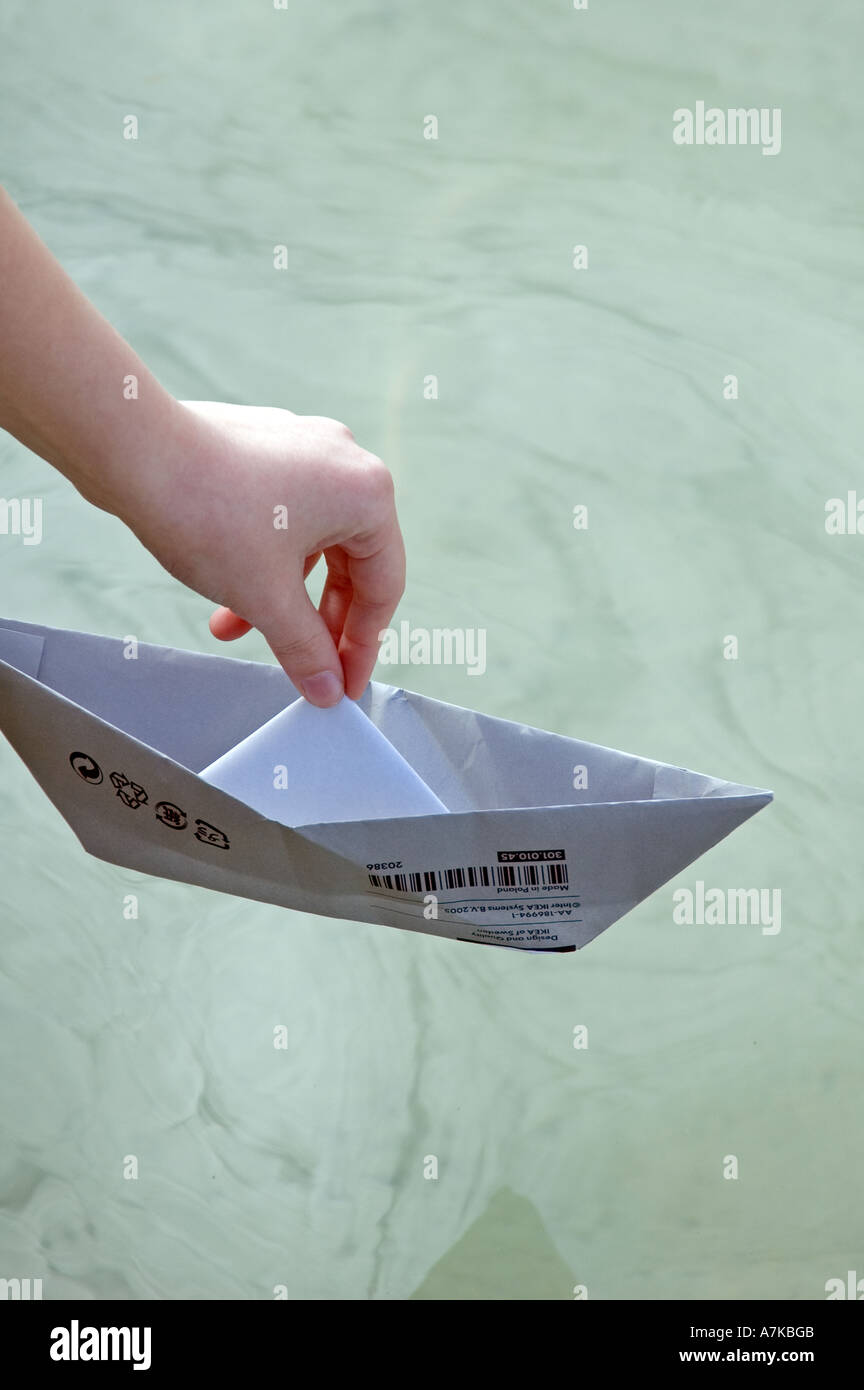 A origami boat folded from paper lowered into the water pool Stock ...