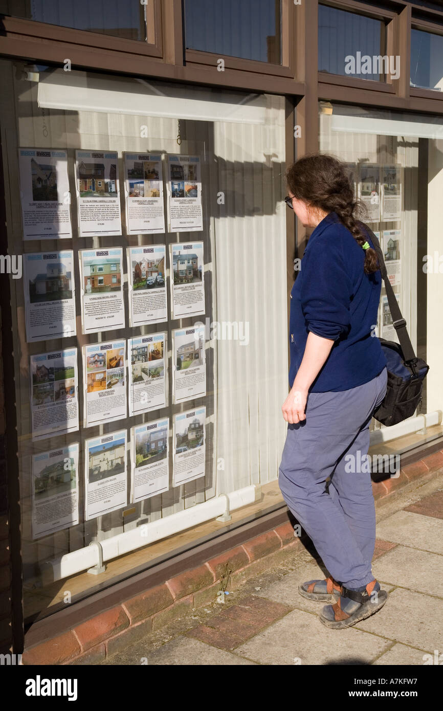 Woman looking at details of houses in estate agent window Caerphilly ...