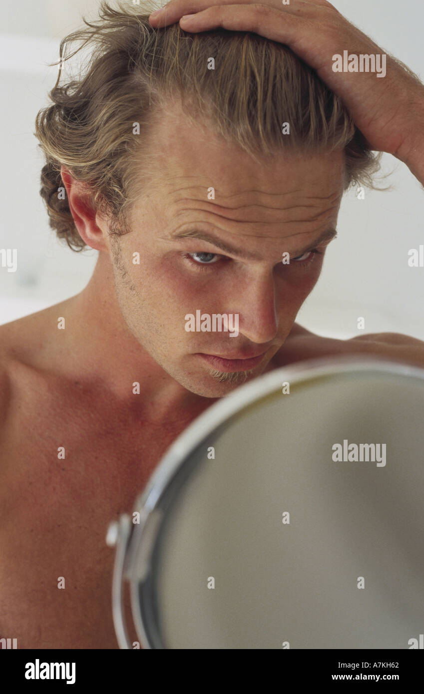 Young man looking into a mirror Stock Photo - Alamy