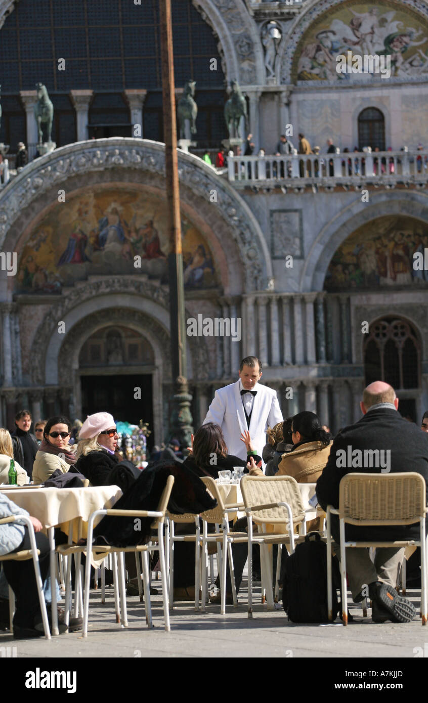 Italian waiter serves tourists in street cafe famous St. Saint Marks ...