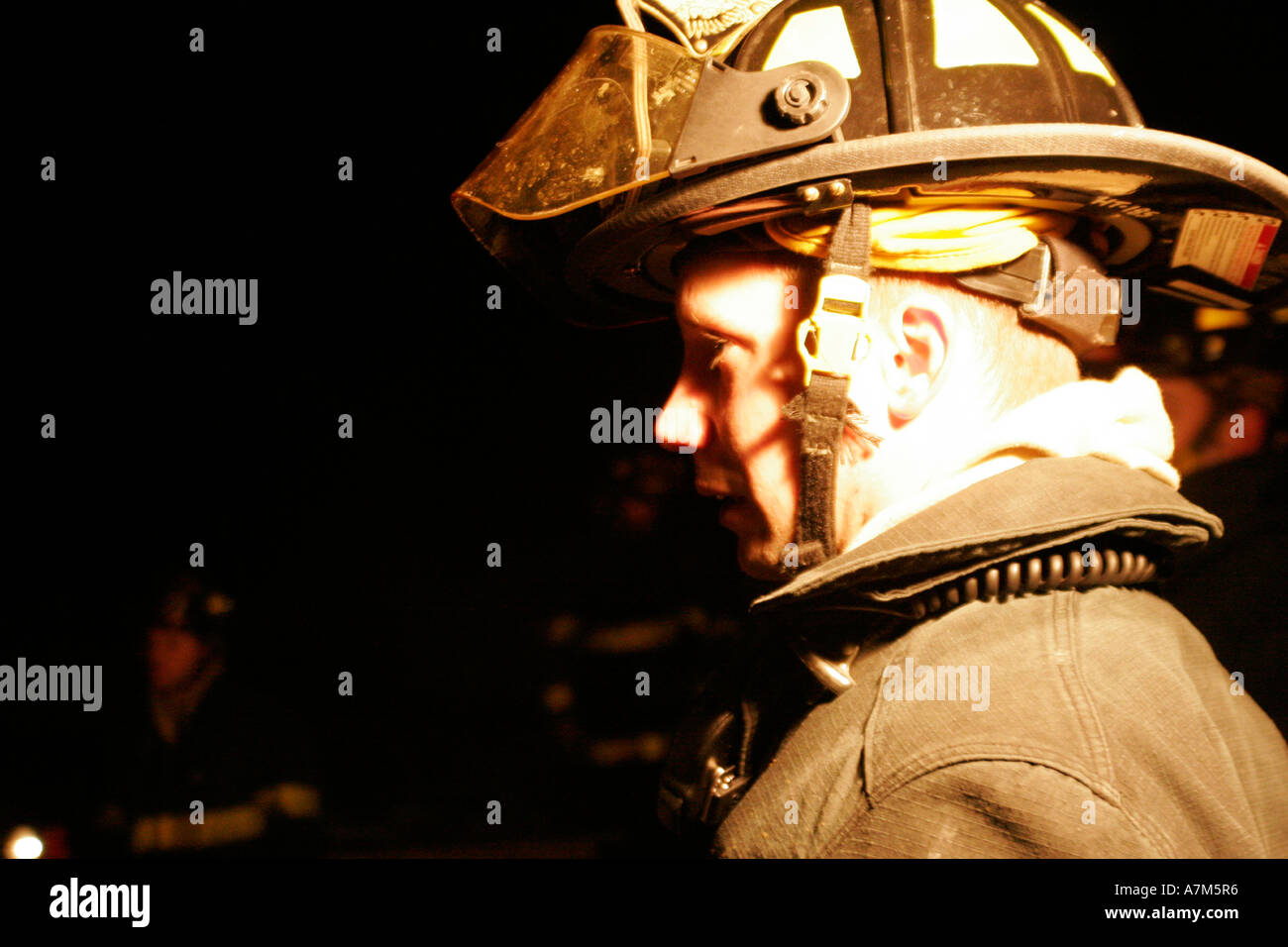 A fire fighter on the scene of an emergency with other fire fighters in ...