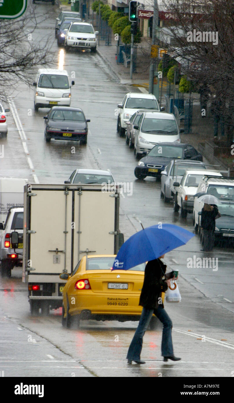 Pedestrian crosses road in wet weather conditions Stock Photo - Alamy