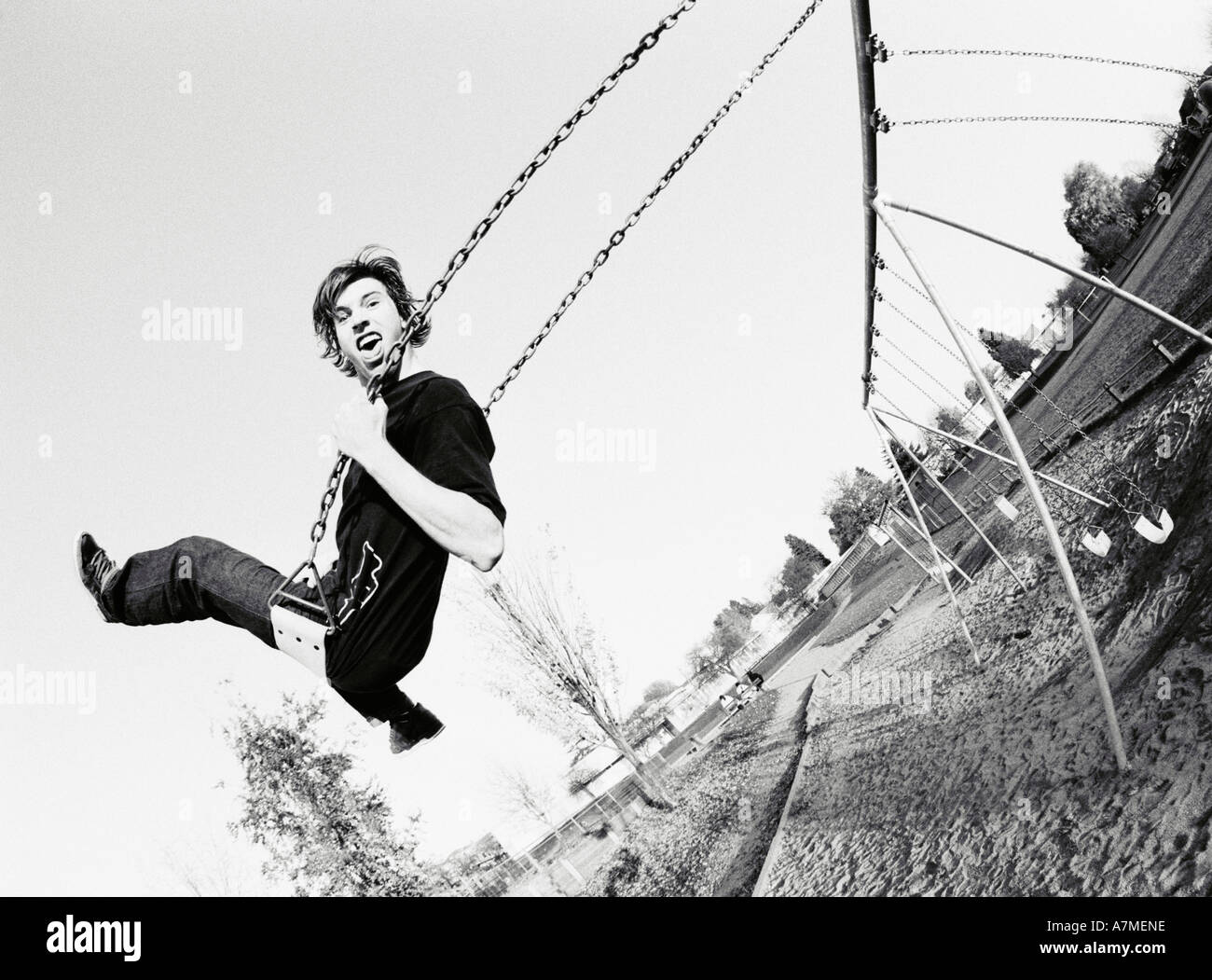 Two young men on swings in playground Stock Photo - Alamy