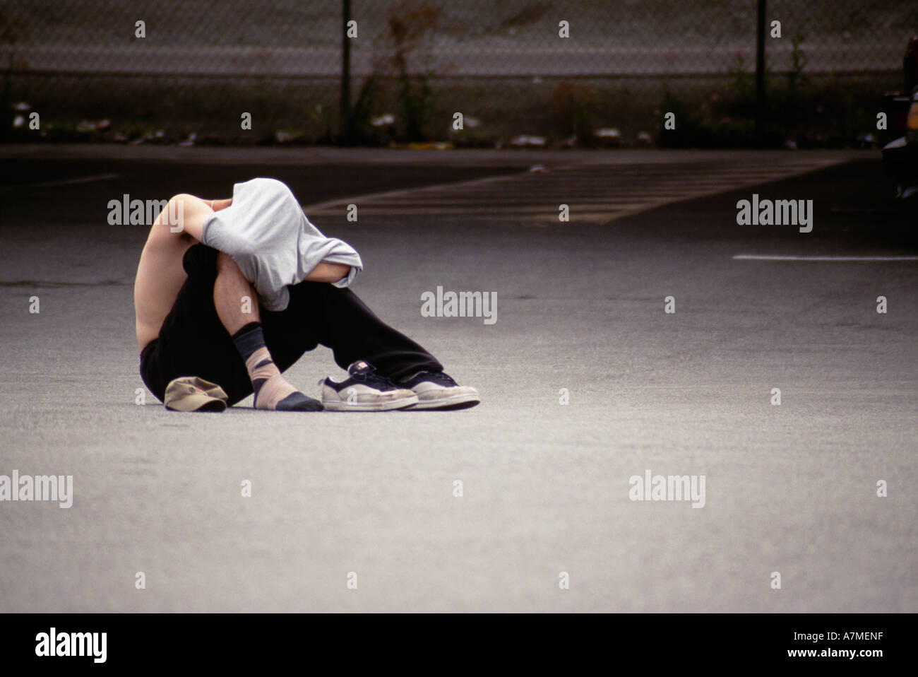 Young man sitting down and covering his head Stock Photo - Alamy