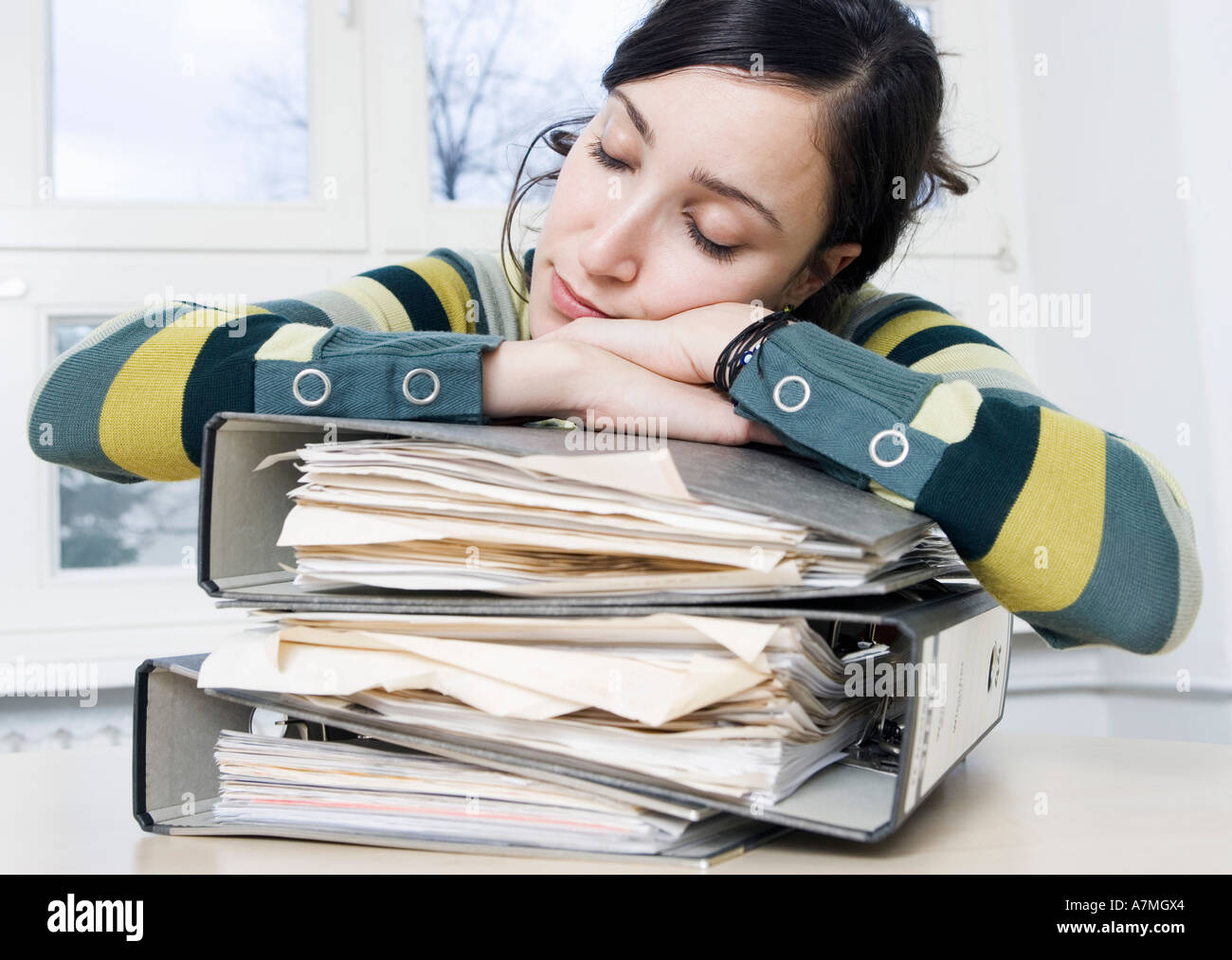 A woman sleeping on a stack of binders in an office Stock Photo - Alamy