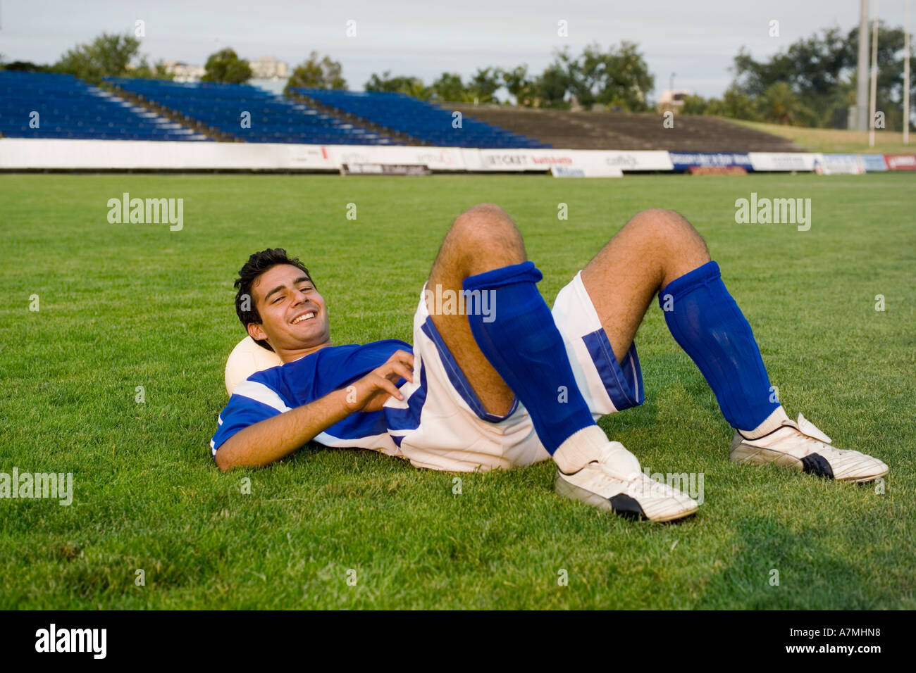 A soccer player resting on a soccer ball Stock Photo - Alamy