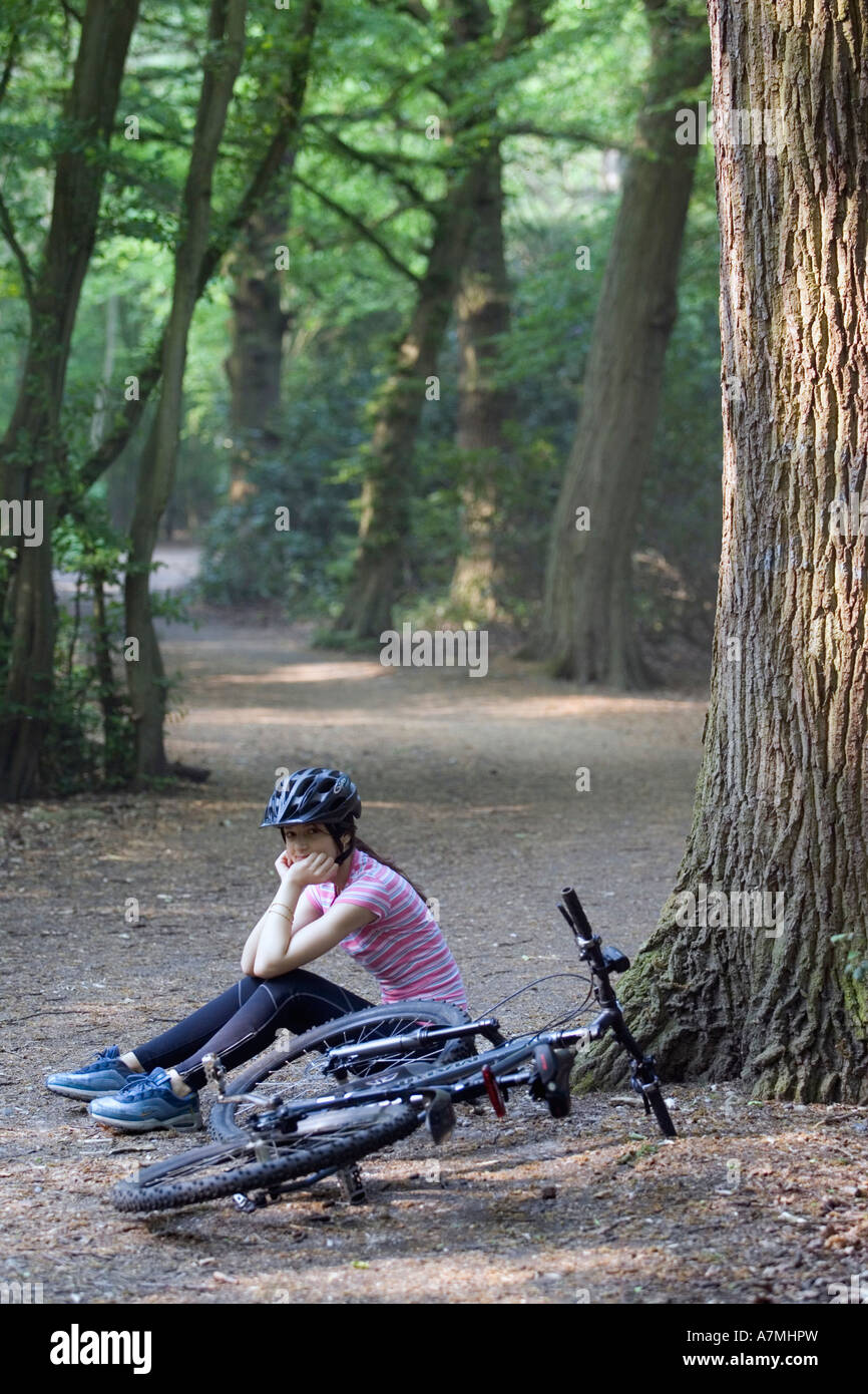 Girl sitting on ground after falling off her mountain bike riding along ...