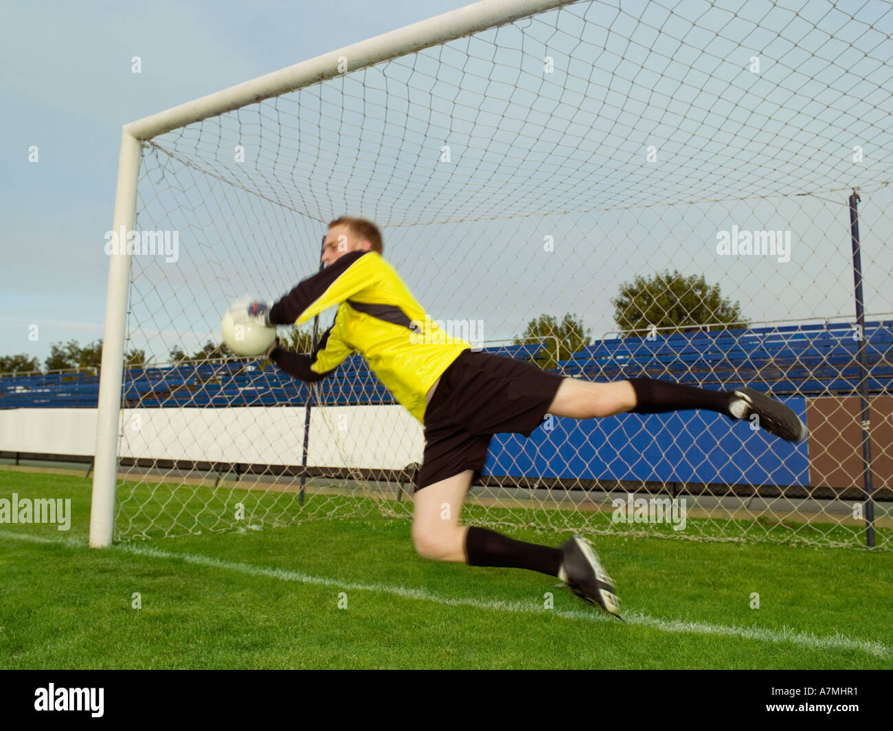 A soccer goalkeeper jumping to block the ball Stock Photo - Alamy