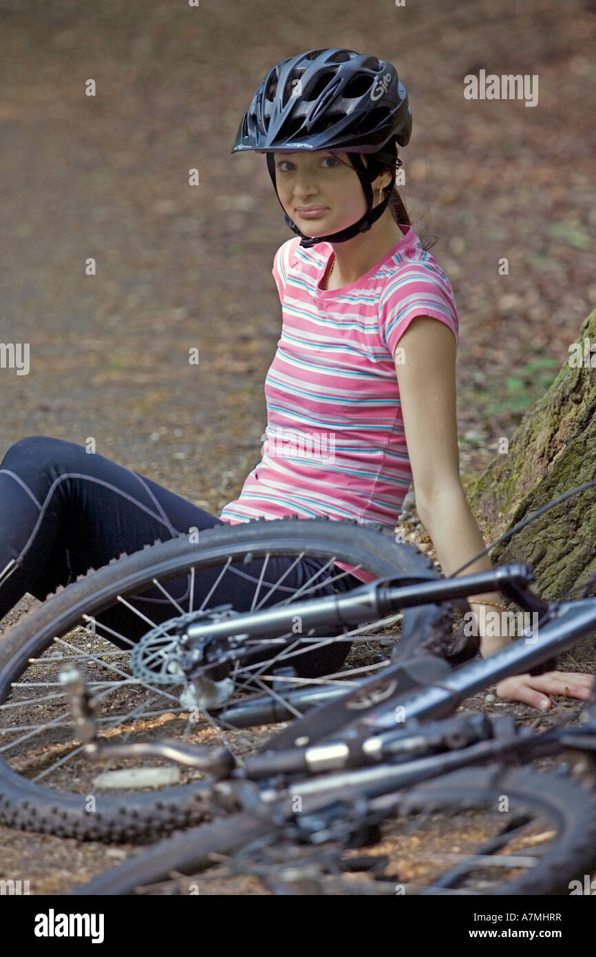 Girl sitting on ground after falling off her mountain bike riding along ...