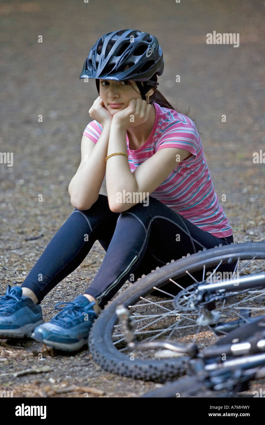 Girl sitting on ground after falling off her mountain bike riding along ...