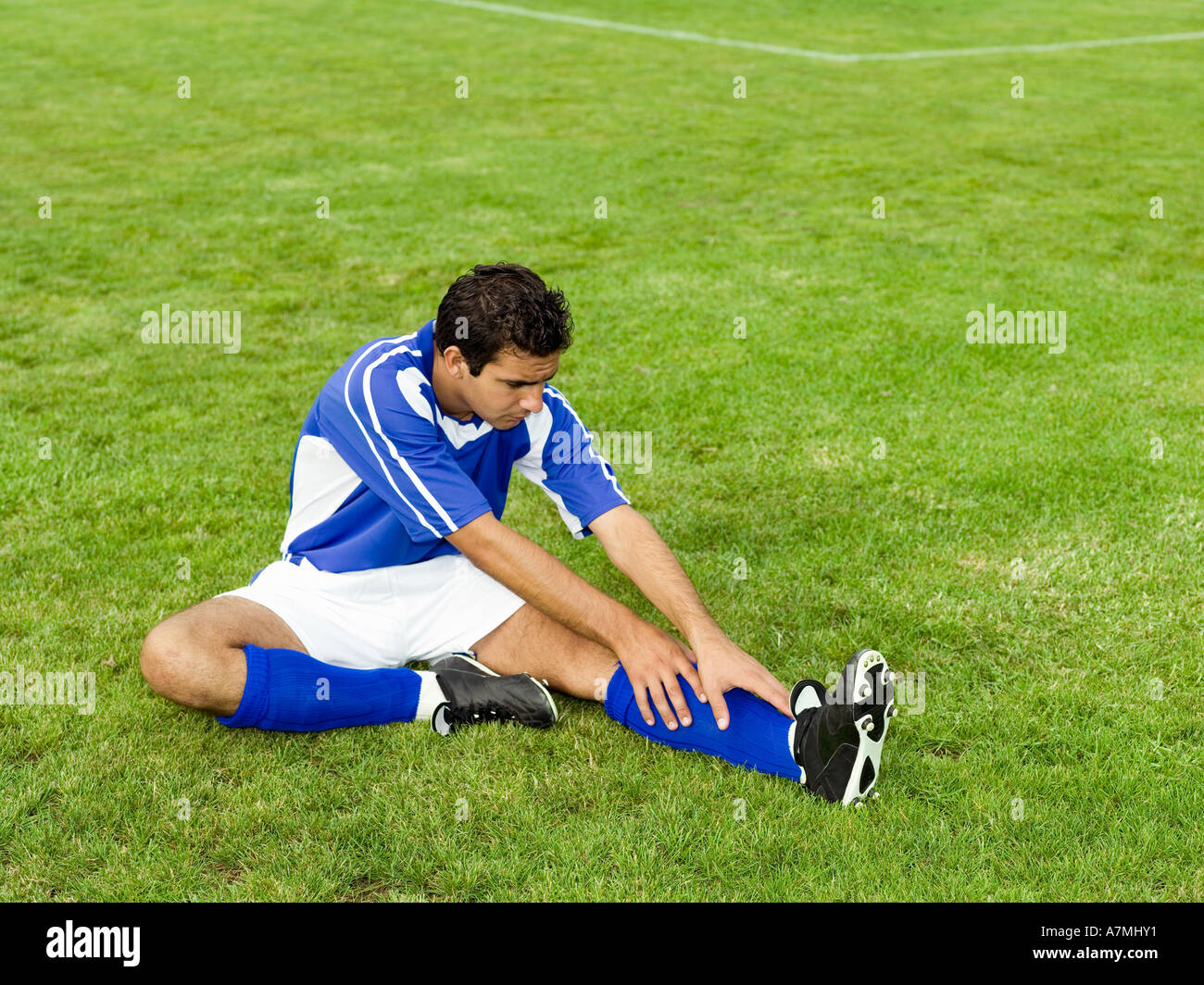 A soccer player stretching on a soccer field Stock Photo - Alamy