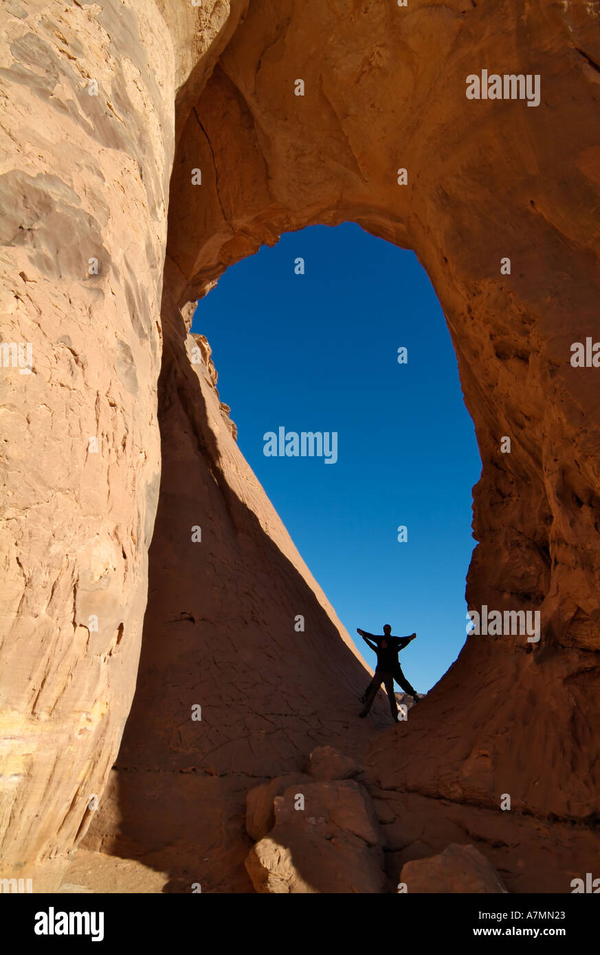 Tourists exploring a natural arch, Jebel Acacus, Sahara Desert, Libya ...