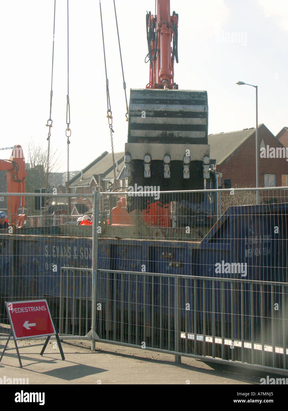A mechanical digger is dropping rubble into a lorry on a construction ...