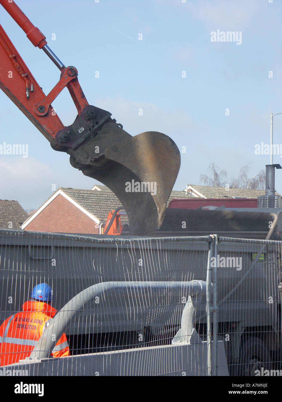 Construction worker on building site, a mechanical digger is dropping ...