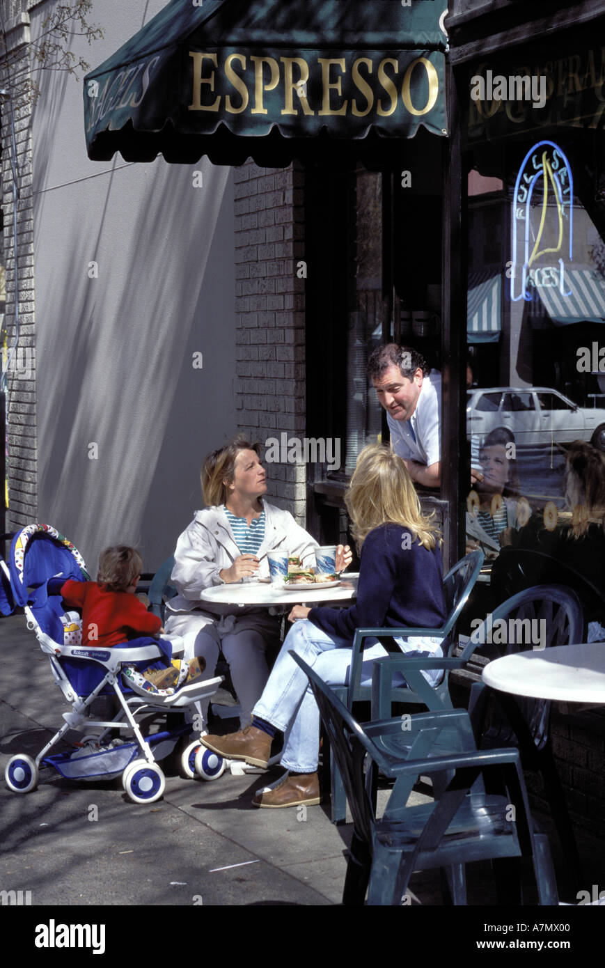 Restaurant waiter hanging out window to talk with two customers eating ...