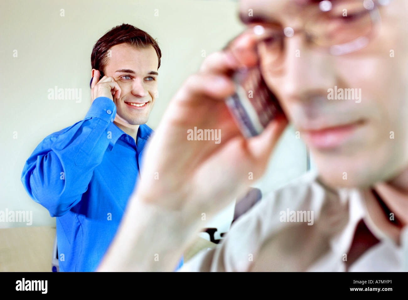 Two men talking on the phones in the office Stock Photo - Alamy