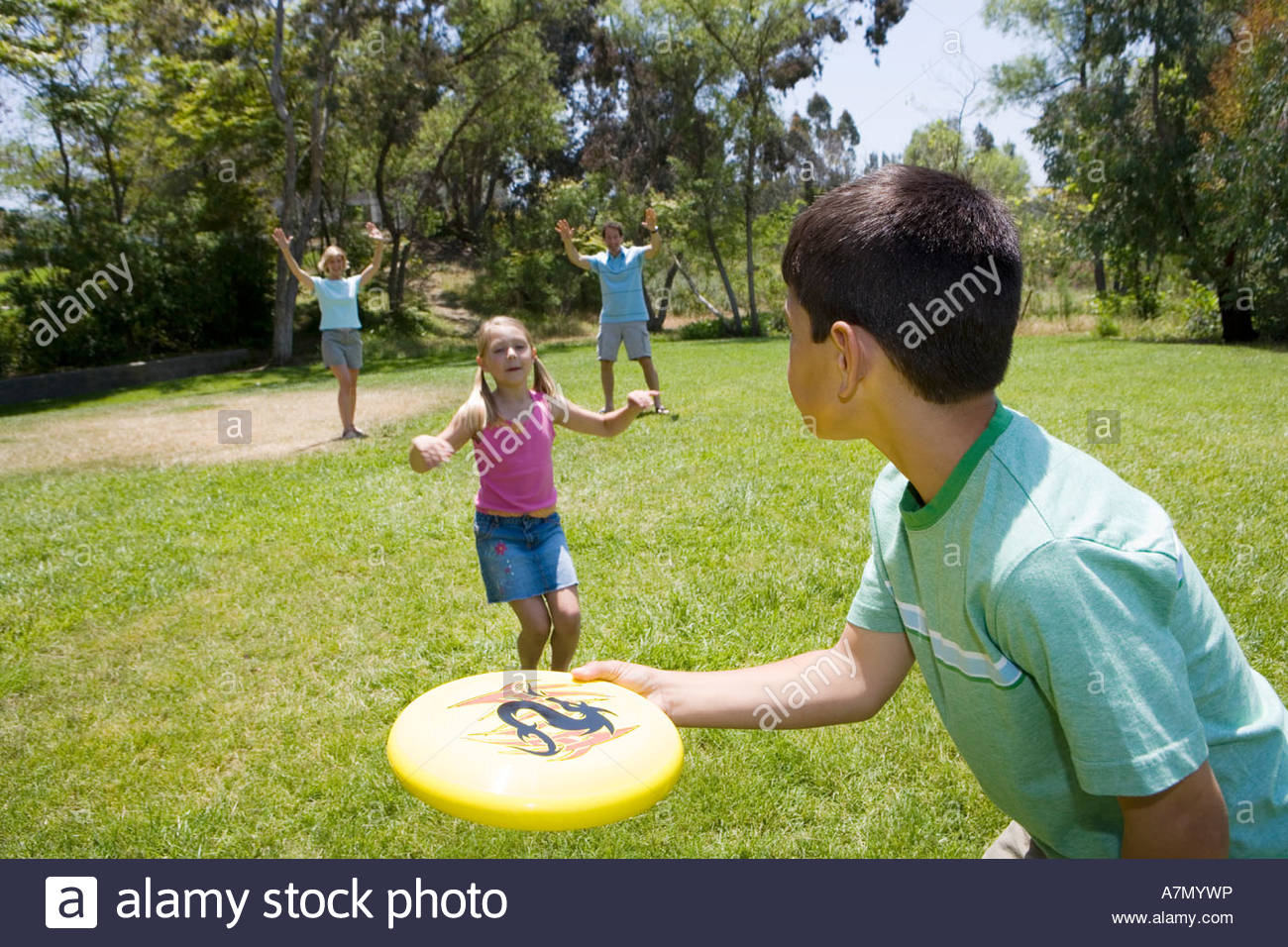 Family playing frisbee in park boy 9 11 throwing disc to parents girl ...